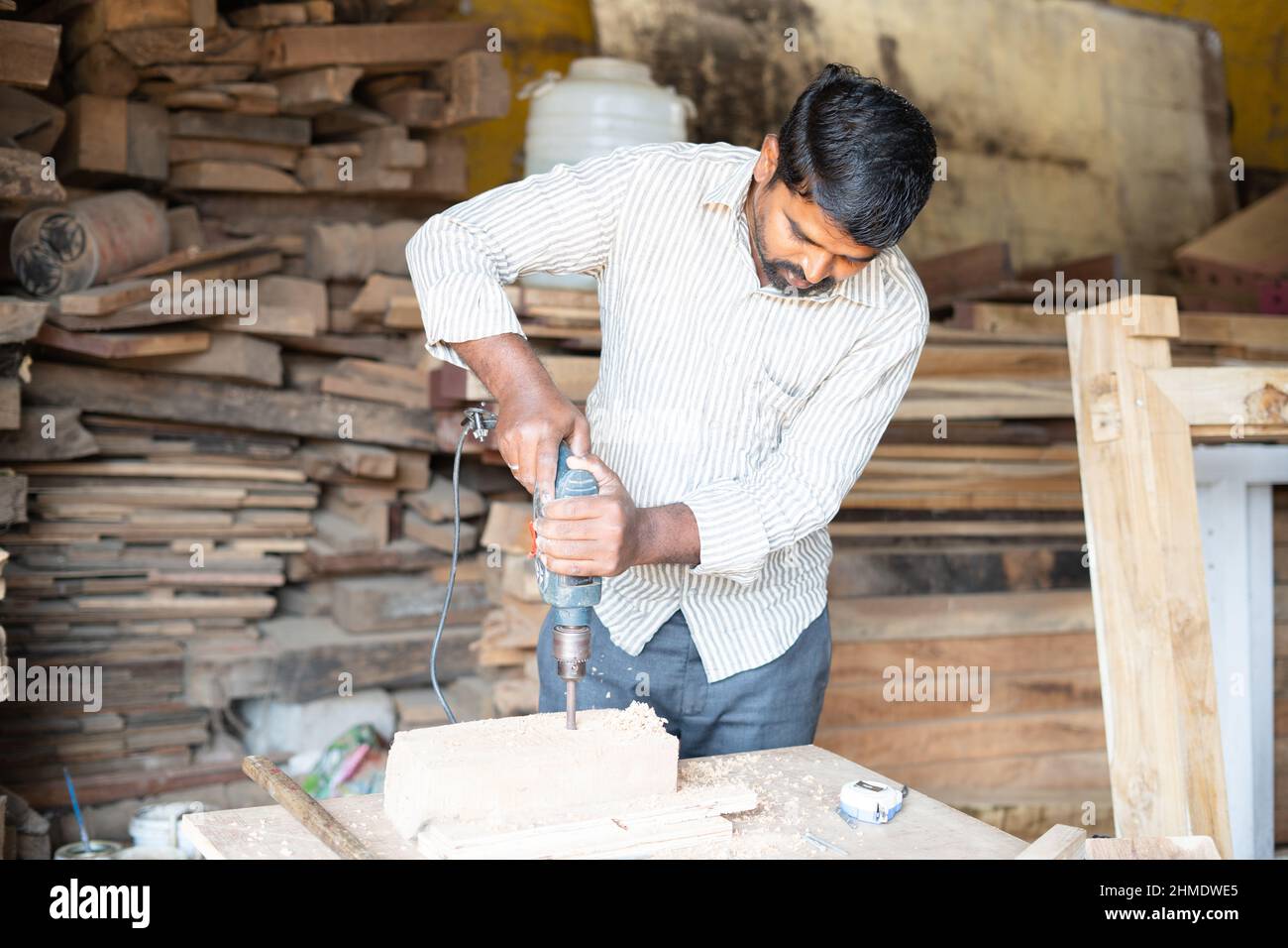 carpenter drilling wood using machine at workshop - concept of ...