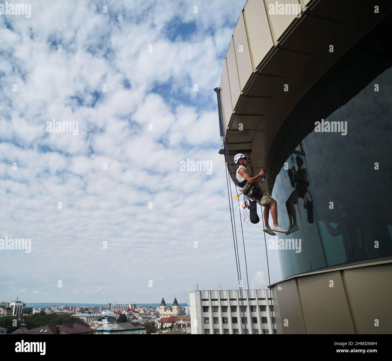 Industrial mountaineering worker hanging on climbing rope and cleaning ...