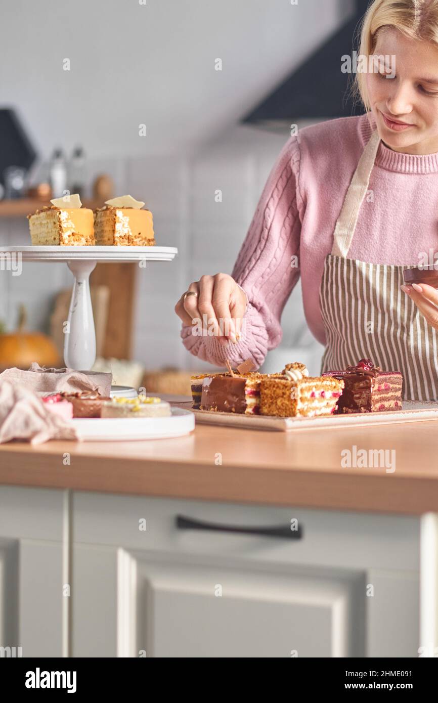 Beautiful smiling female pastry chef prepares desserts in a cozy ...