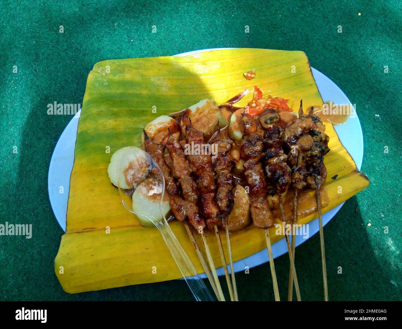 Sate and lontong (rice cake, rice roll) on the plate and banana leave ...