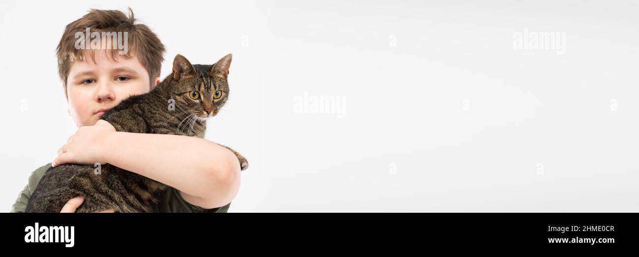 Close-up view of a boy holding a she-cat in his arms and hugging her ...