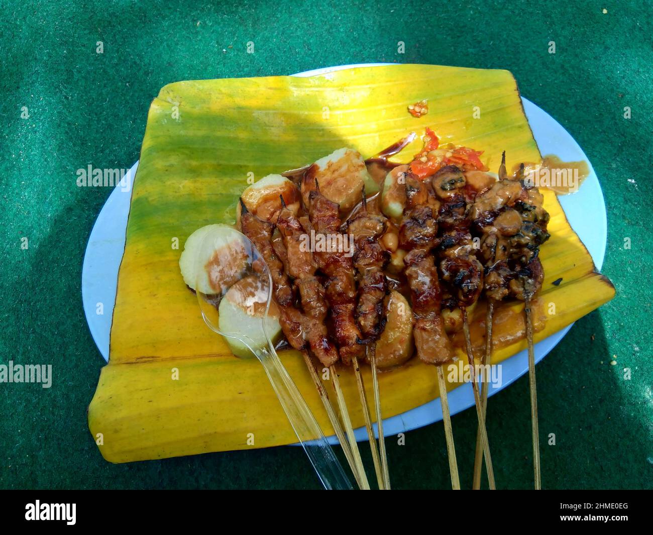 Sate and lontong (rice cake, rice roll) on the plate and banana leave ...
