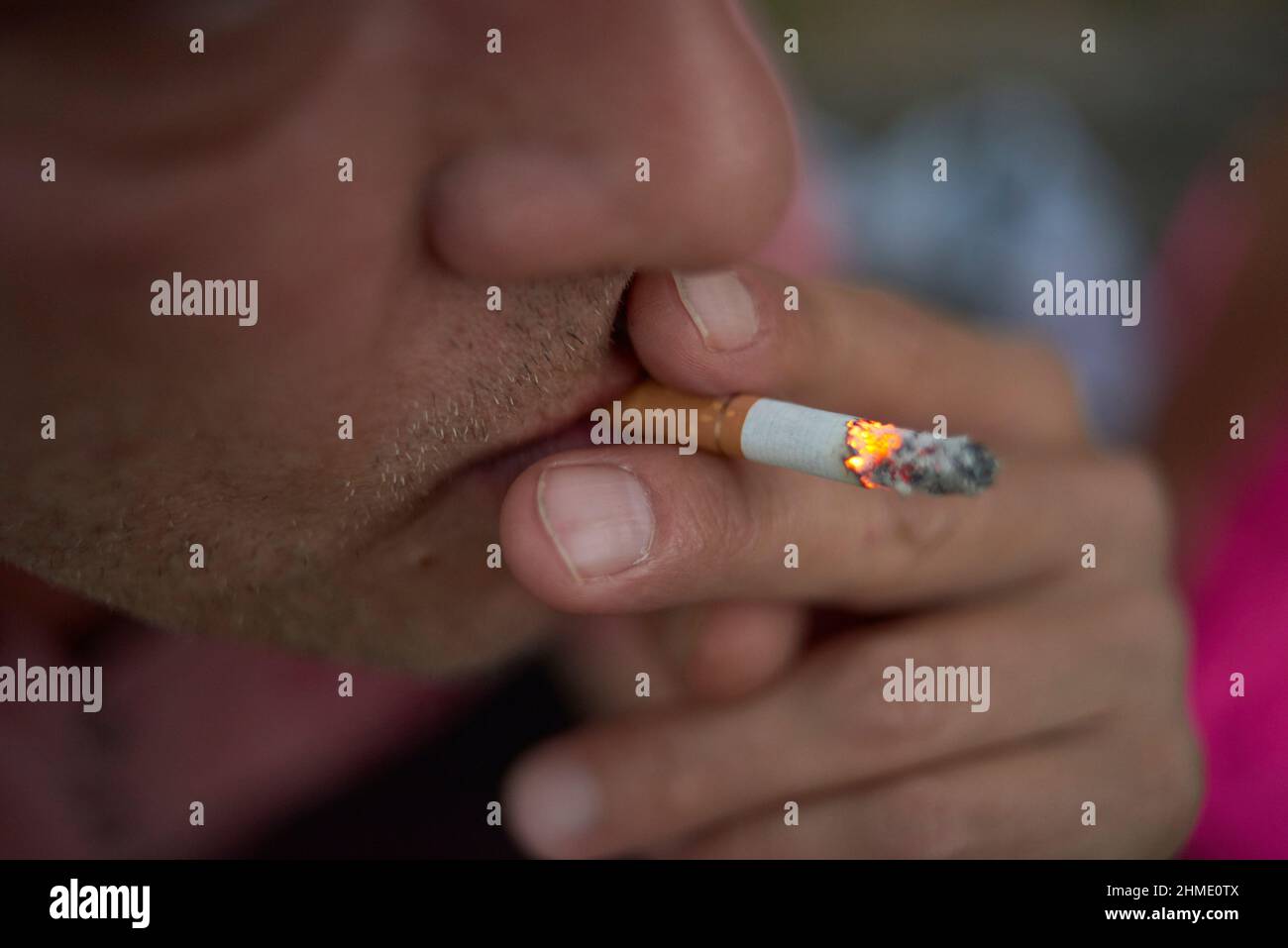 Close up of a man smoking a cigarette outdoors in a park Stock Photo ...