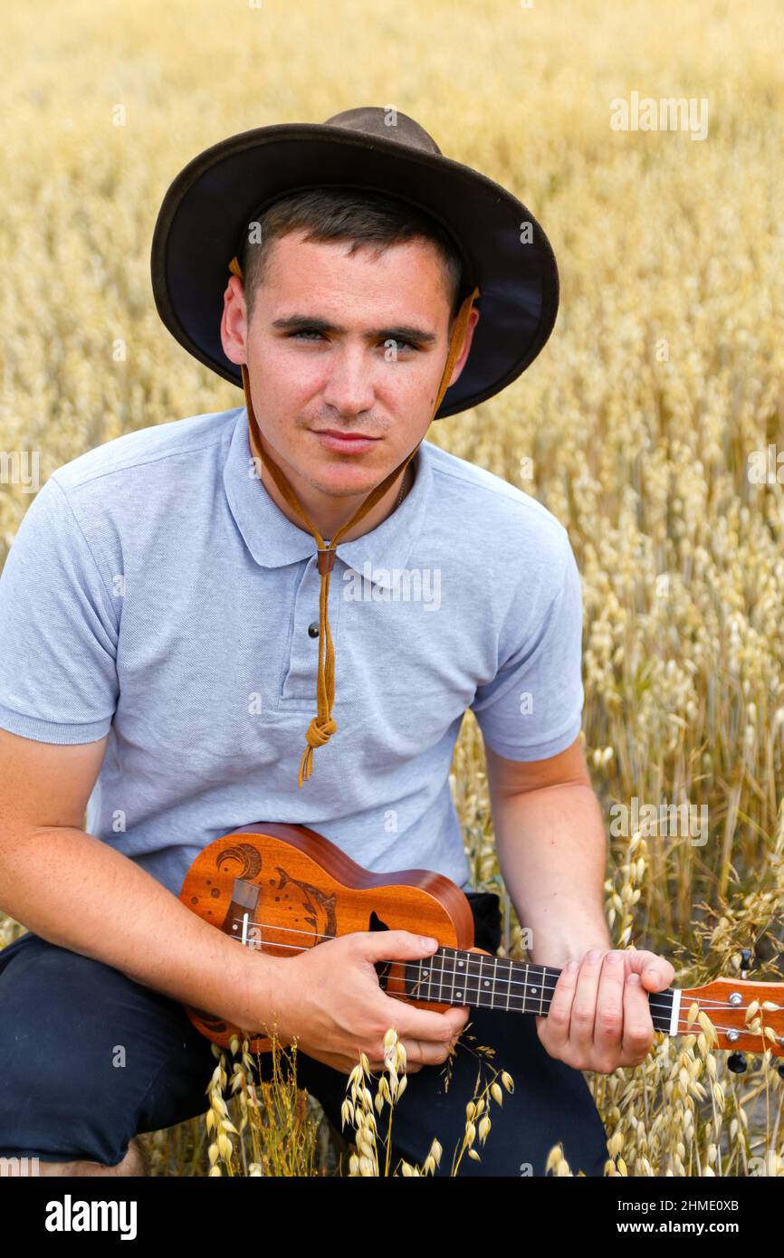 Vintage musician. Young beautiful caucasian man playing ukulele outside ...