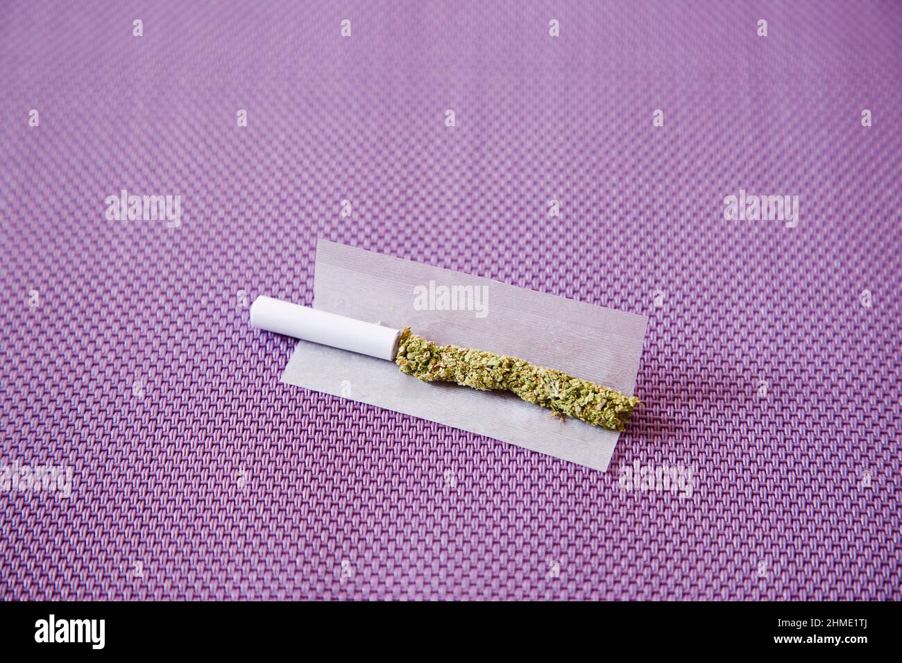 marijuana in rolling cigarette, mouthpiece, paper, purple background ...