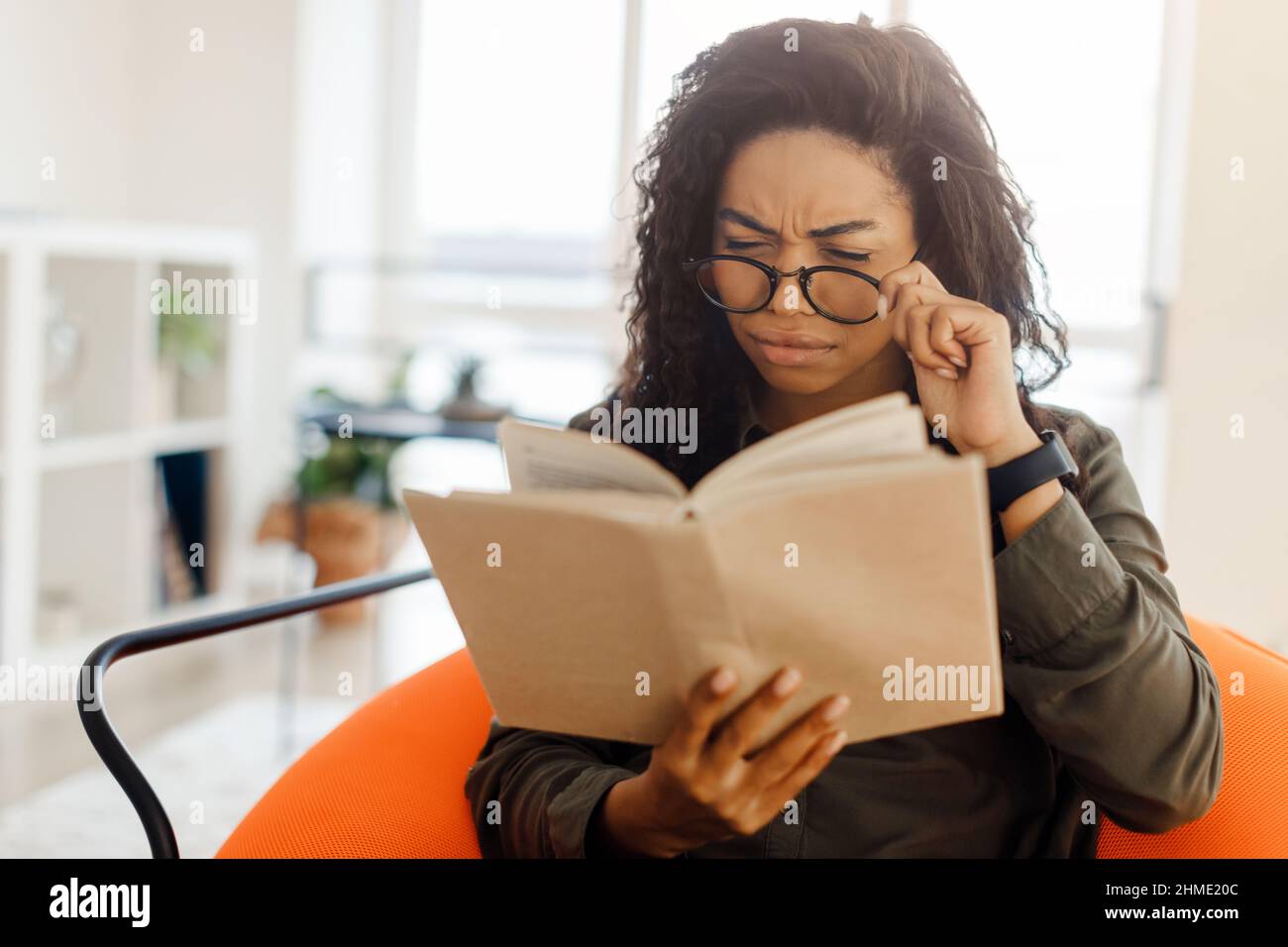Focused black lady in glasses trying to read book Stock Photo - Alamy