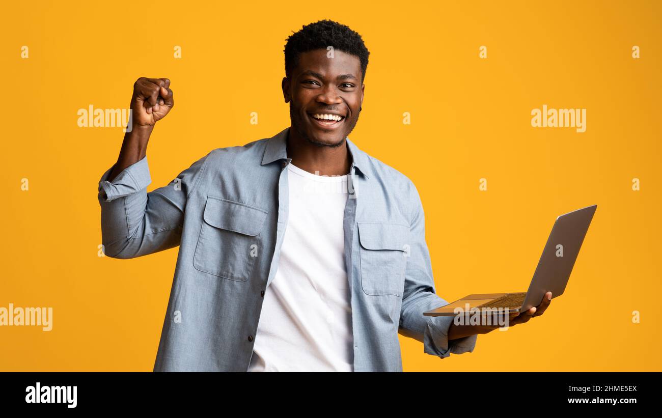 Happy african american guy holding laptop and gesturing Stock Photo - Alamy