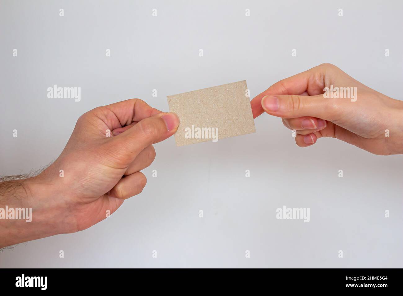Man giving empty business card to woman isolated on gray wall ...