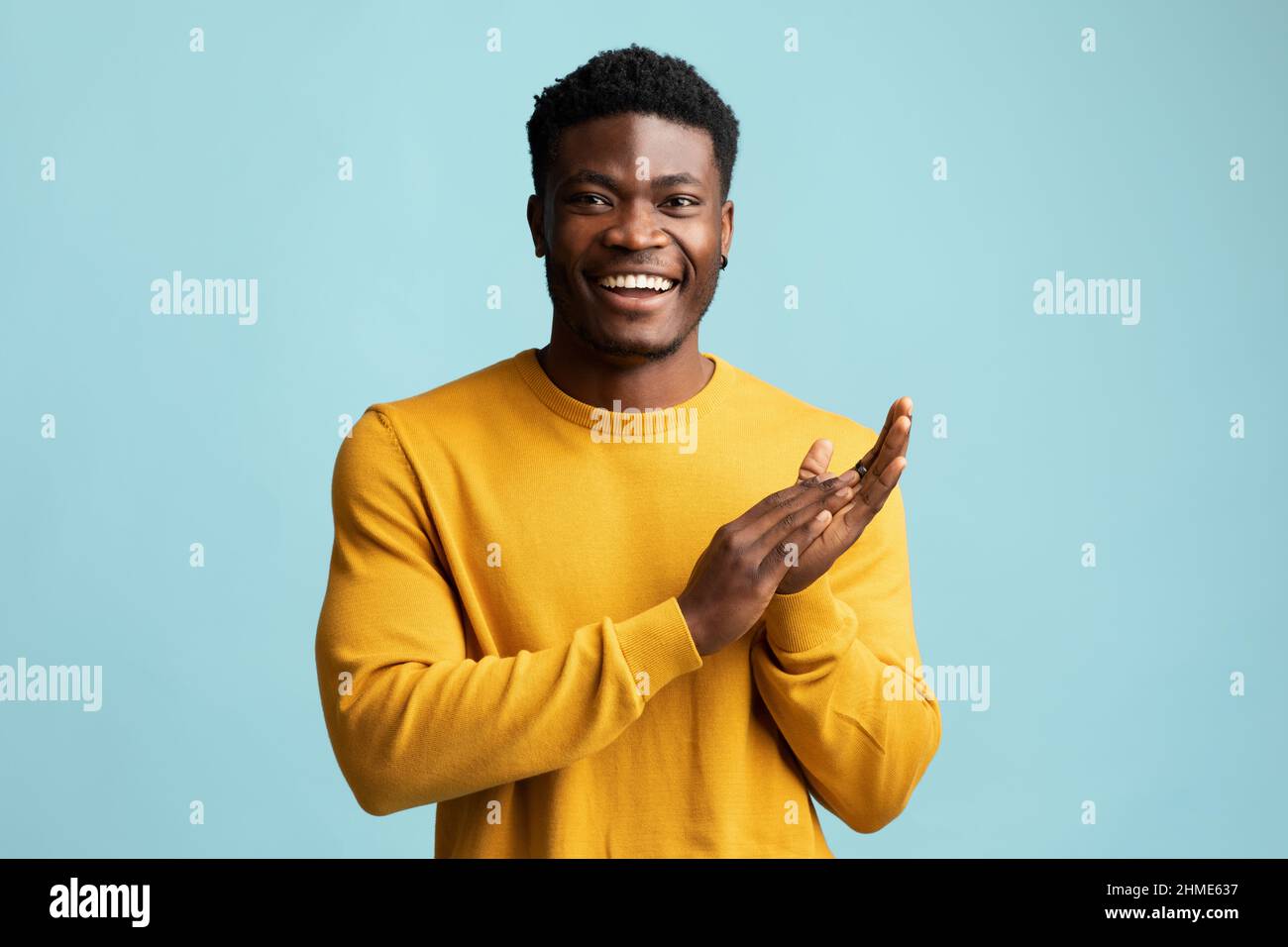 Emotional black guy clapping hands on blue Stock Photo - Alamy