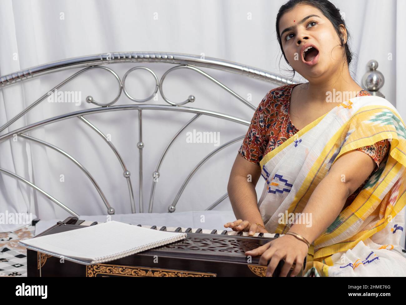 A beautiful Indian woman in saree singing and playing harmonium on ...