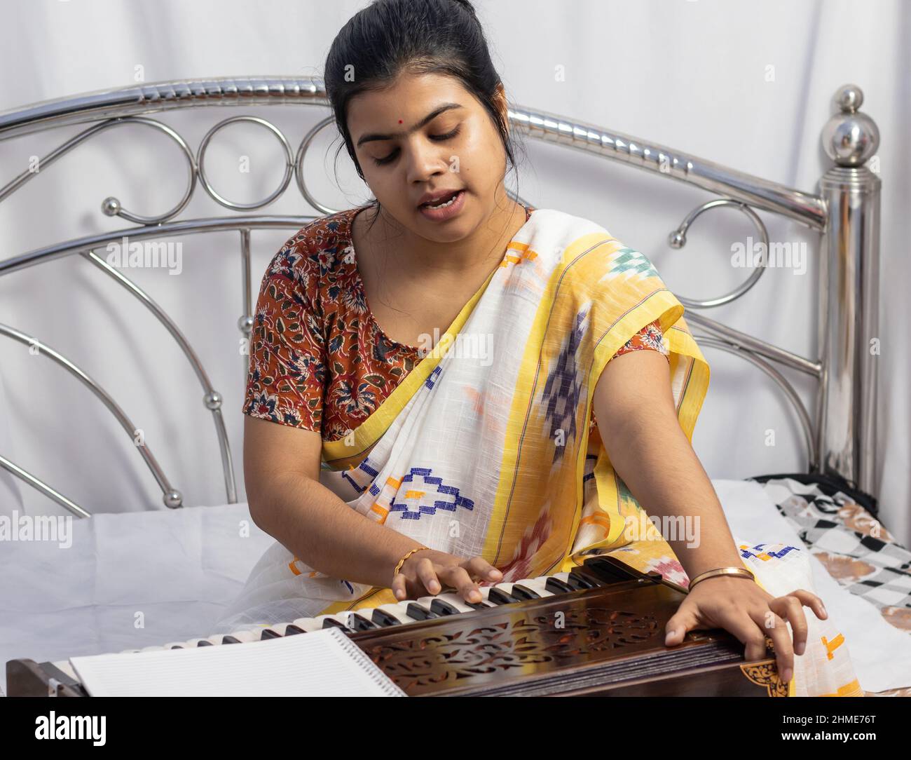 A beautiful Indian woman in saree singing and playing harmonium on ...