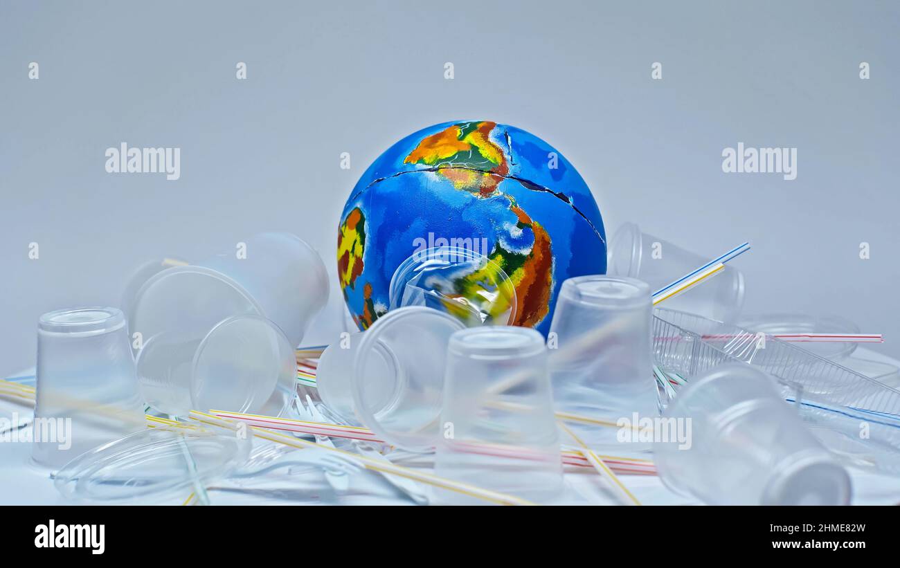 globe near plastic cups and trash on grey, environmental concept Stock ...