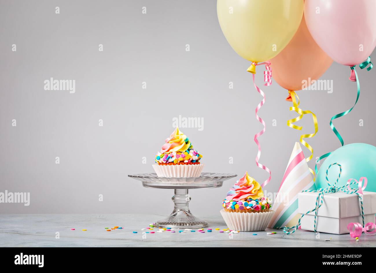 Two Rainbow Birthday cupcakes with presents, hats and colourful ...