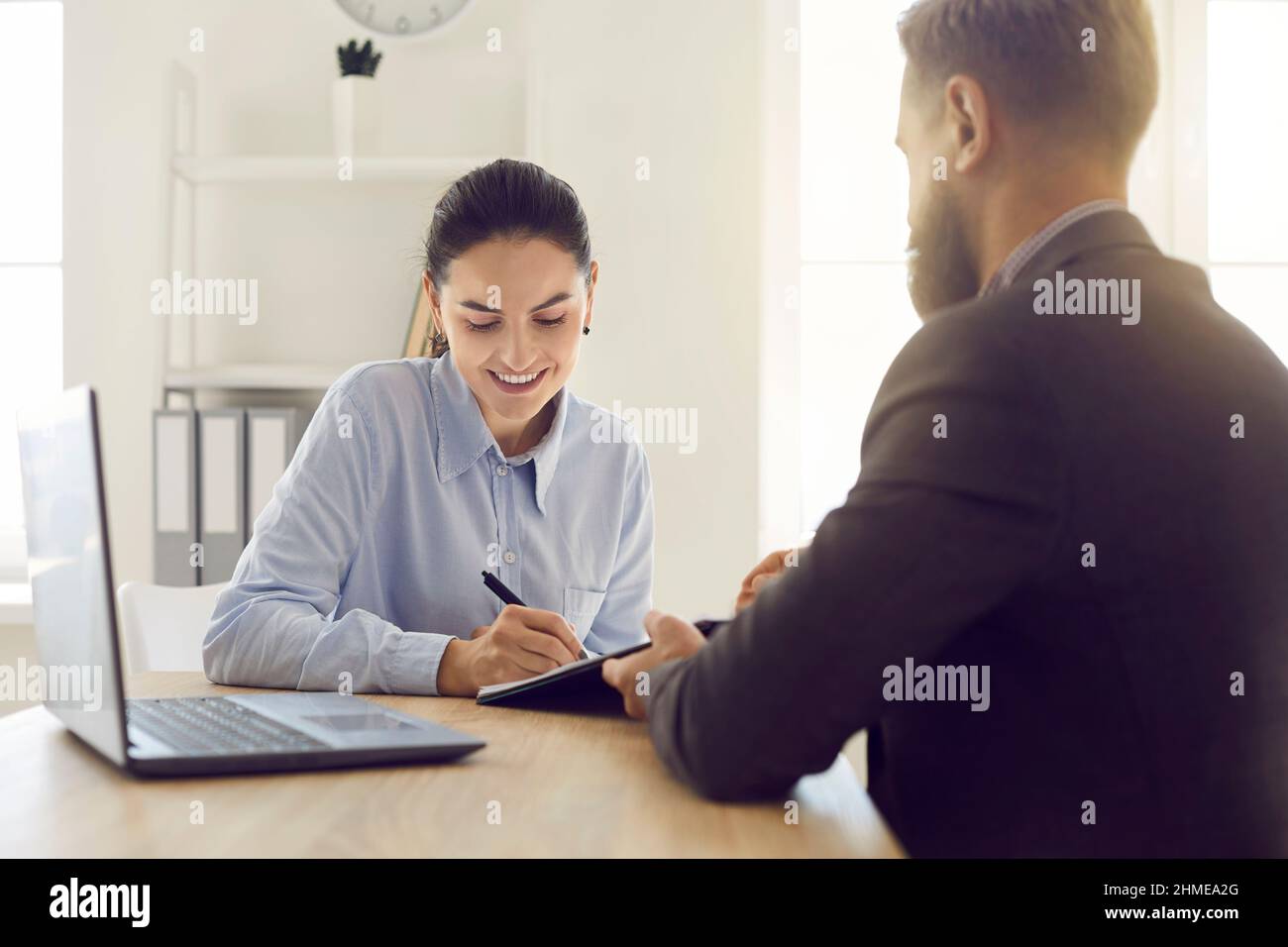 Happy female client during meeting in office signs paper document ...