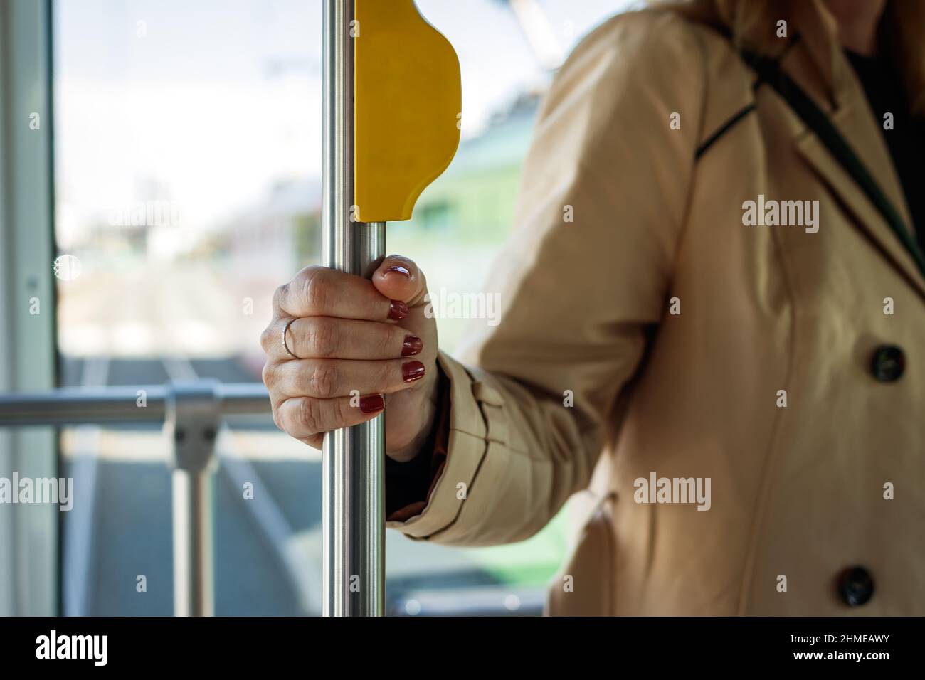 Woman holding pole in city bus. Hygiene risk when holding the handle in ...