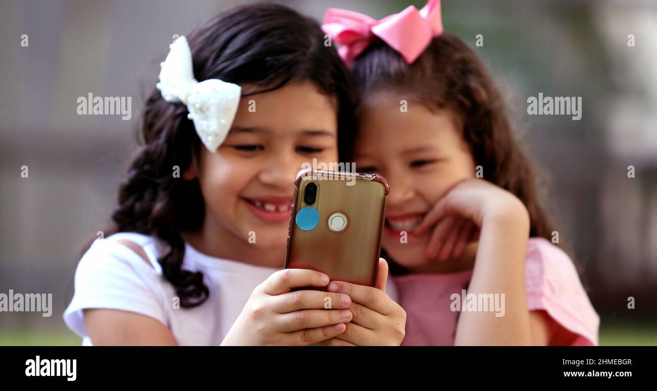 Children addicted to cellphone, two little girls looking at smartphone ...