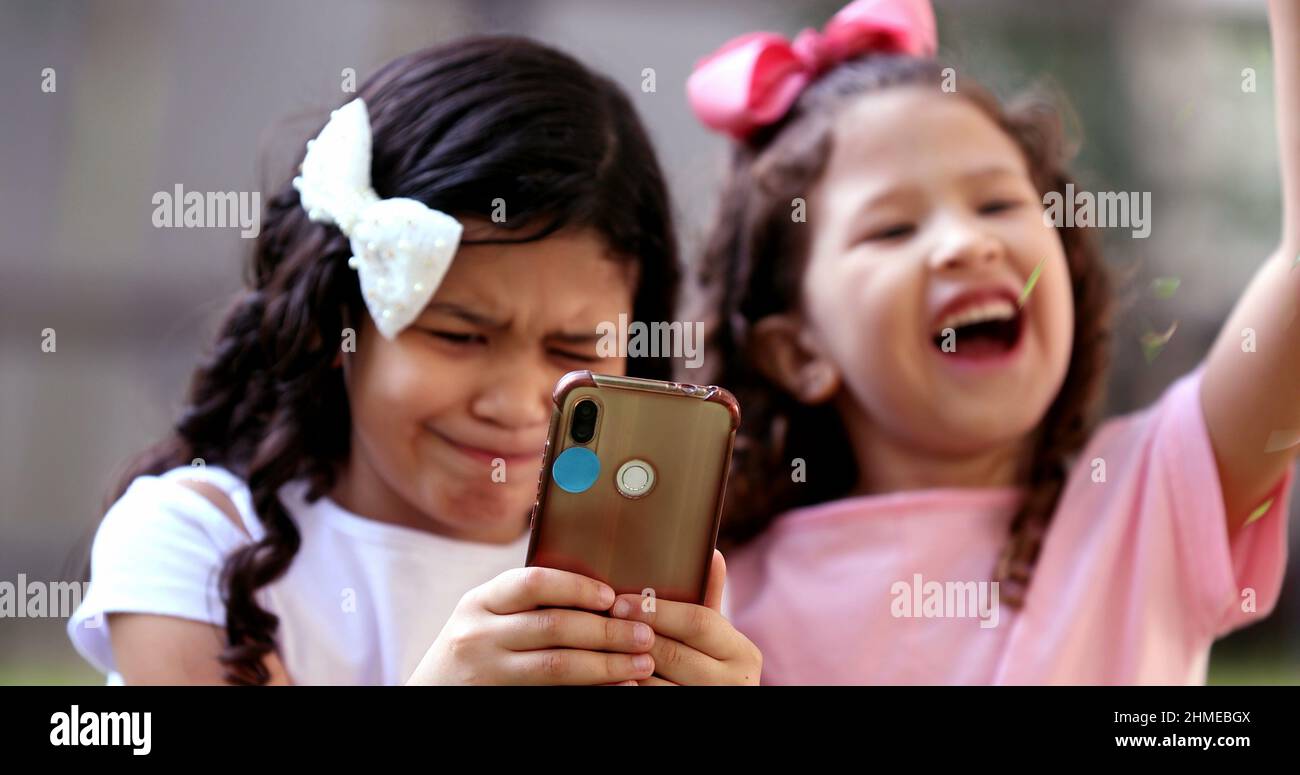 Children addicted to cellphone, two little girls looking at smartphone ...