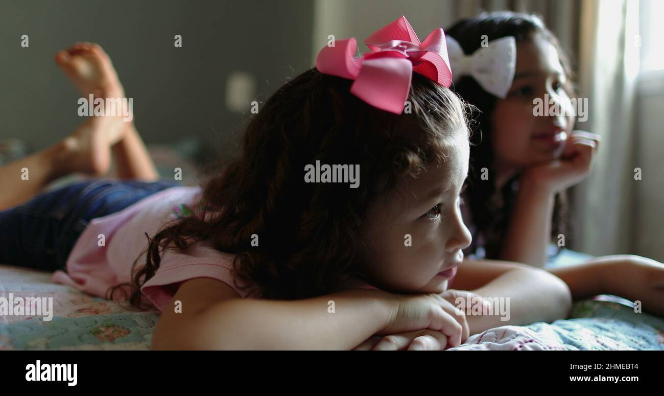 Children lied in bed watching television screen. kid looking at media ...