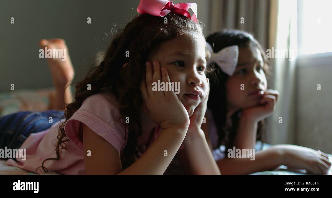 Children lied in bed watching television screen. kid looking at media ...