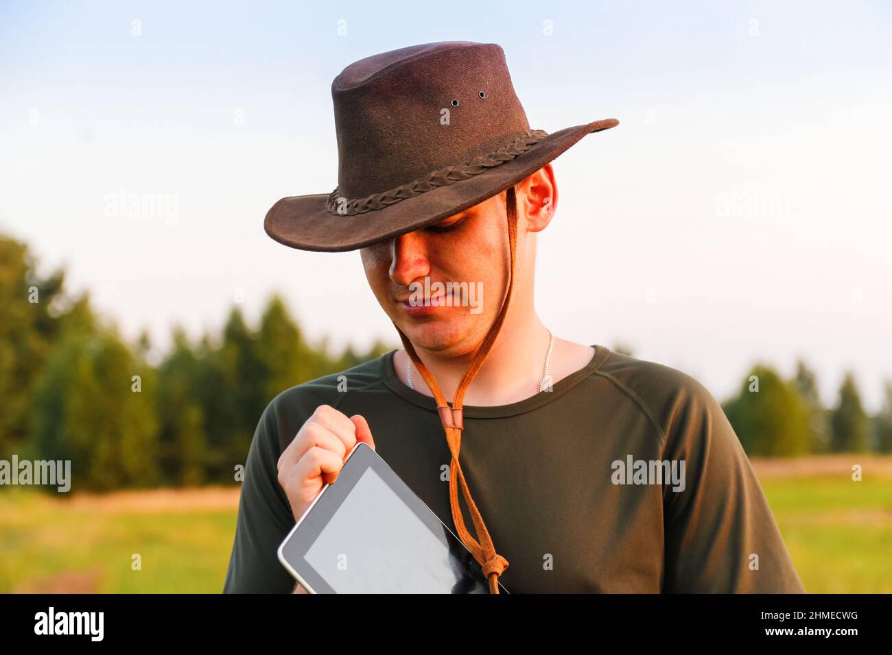 Young man affected farmer in cowboy hat at agricultural field holding ...