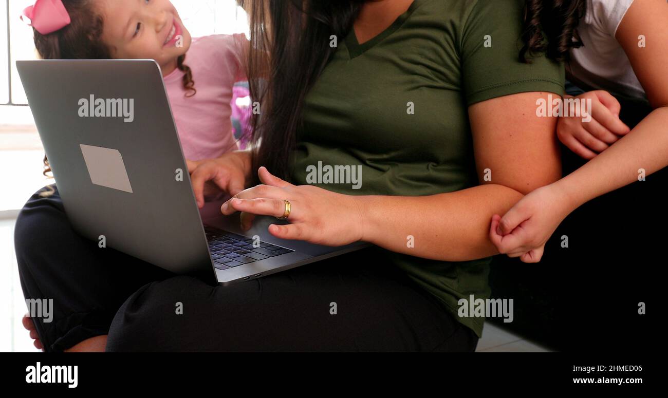 Mother multi-tasking, using computer laptop at home while parenting two children, staying at ...