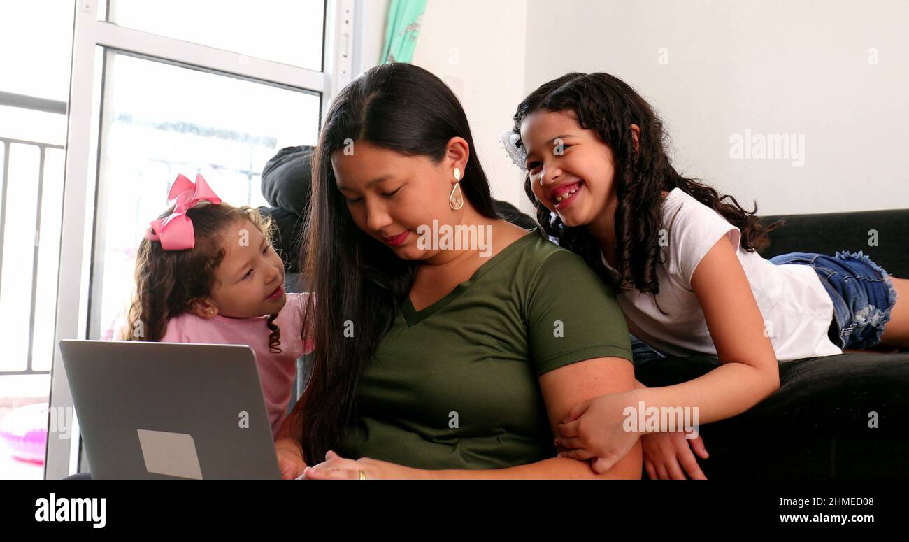 Mother multi-tasking, using computer laptop at home while parenting two ...