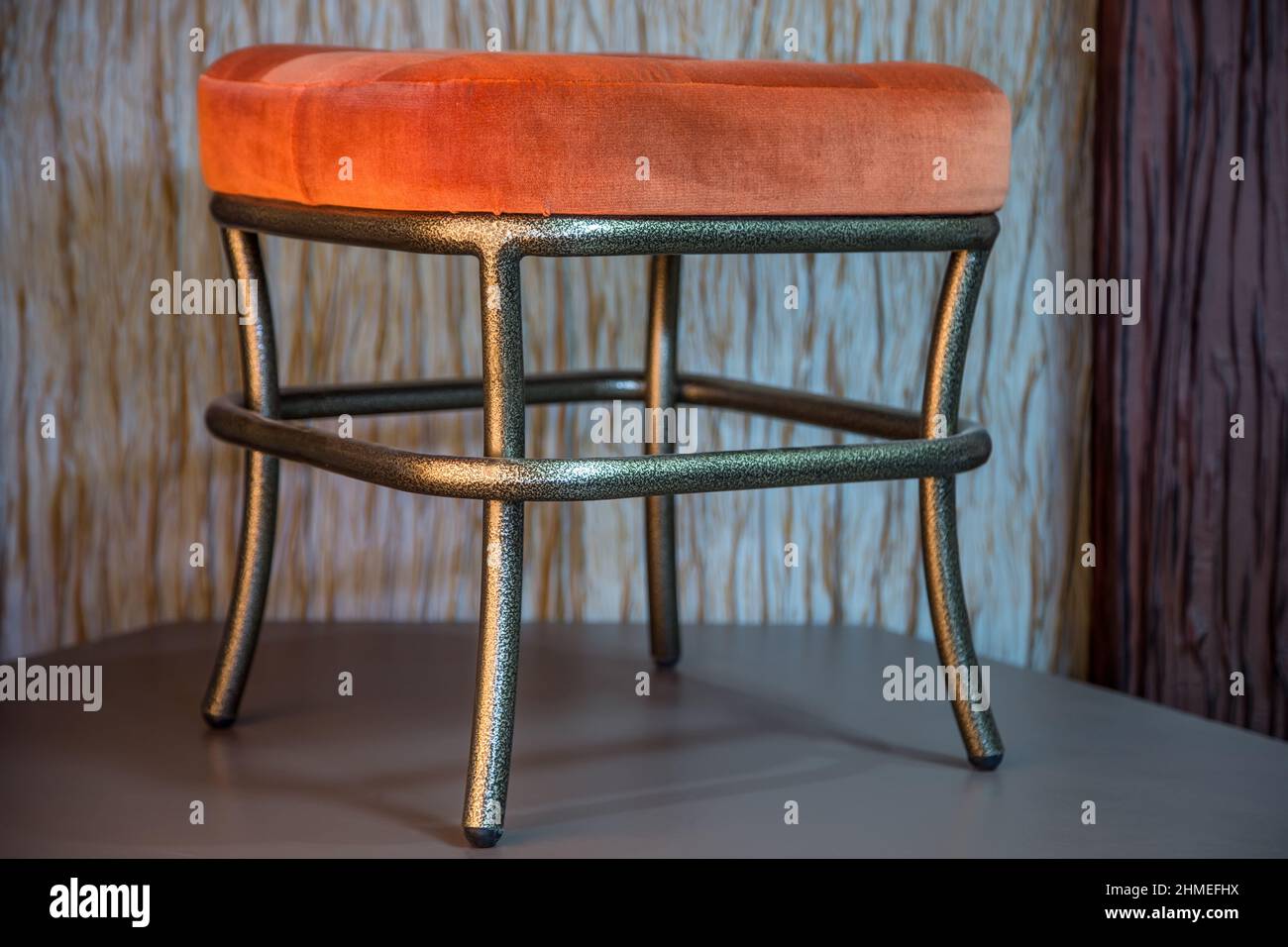 Modern orange stool made of metal on wallpaper background Stock Photo ...