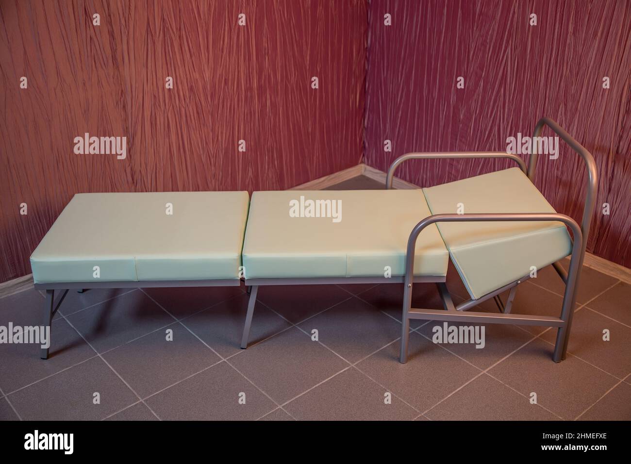 White medical bed standing in the corner of a room with red wallpapers ...