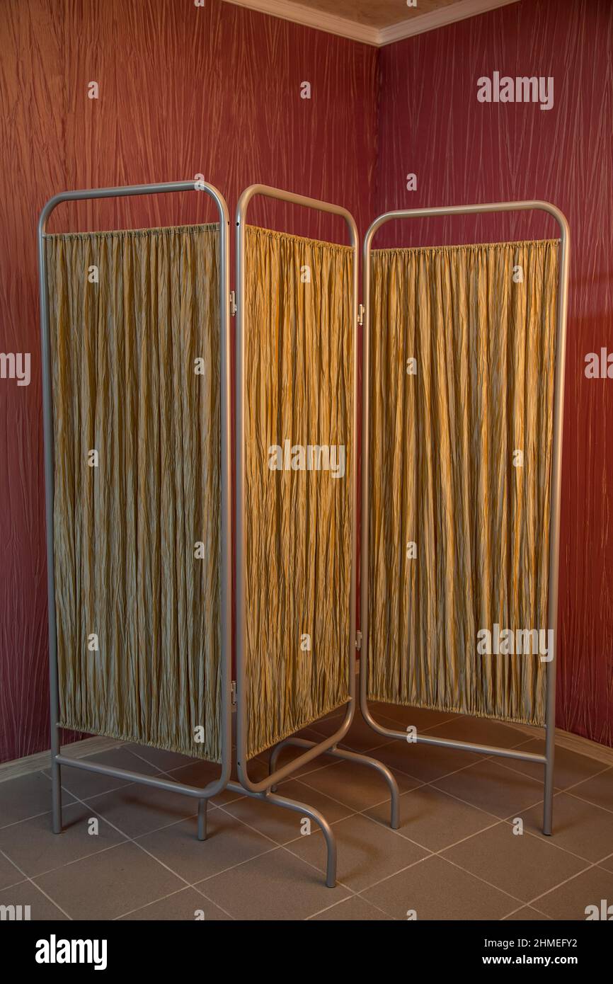 Folding screen standing in the corner of a room with red wallpapers ...