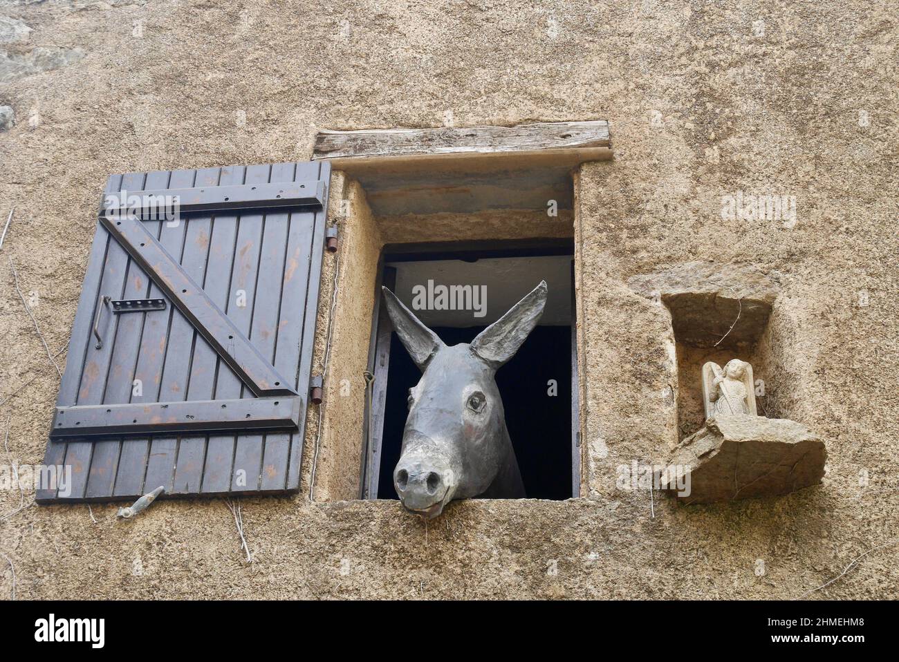 Wooden donkey looking out of the window of a traditional house in Sant ...