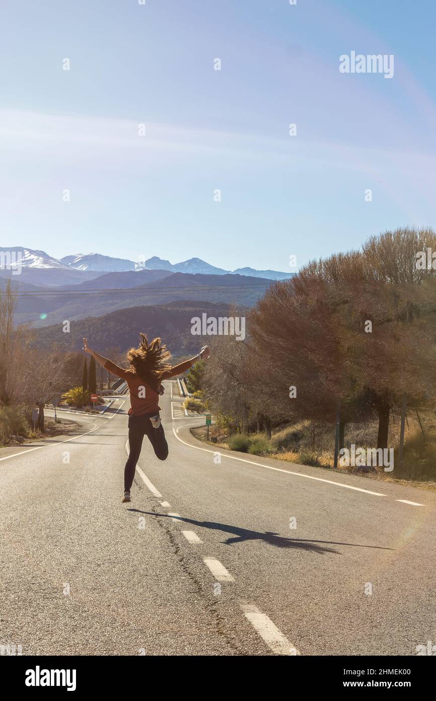 woman seen from behind jumping in the middle of a highway Stock Photo ...