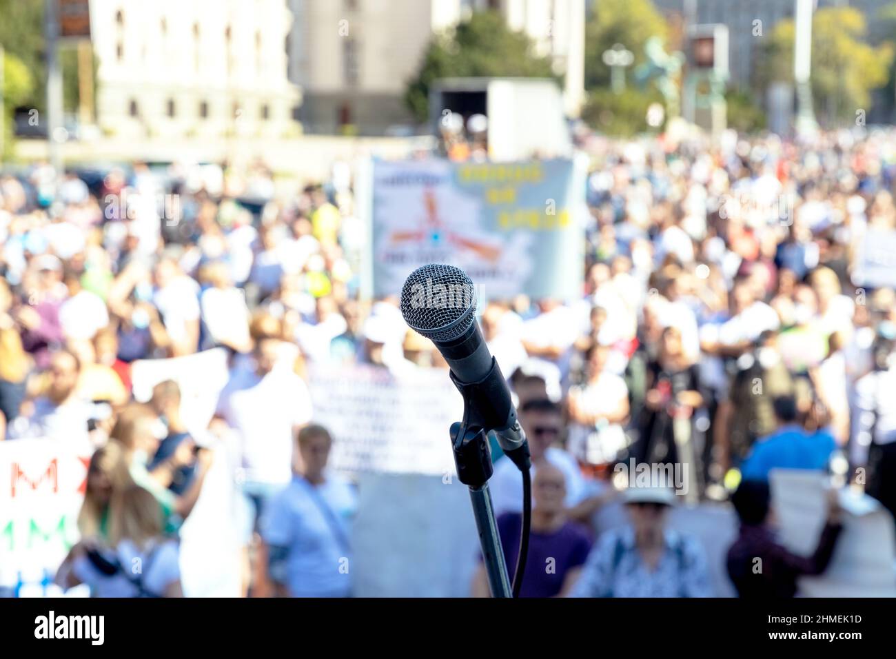 Focus on microphone, blurred group of people at protest or public ...