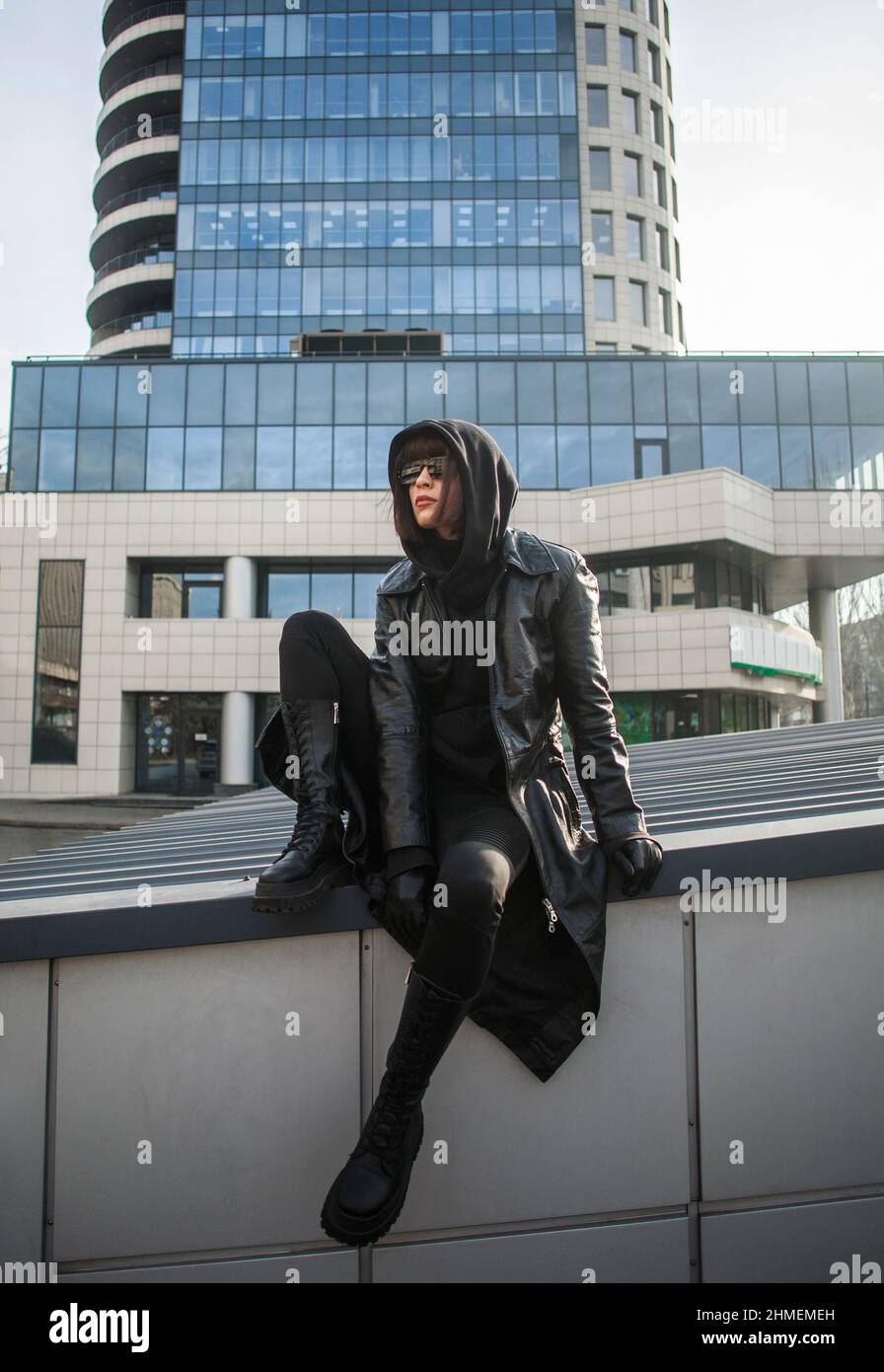 Woman in long leather coat spy agent on the background of a modern ...