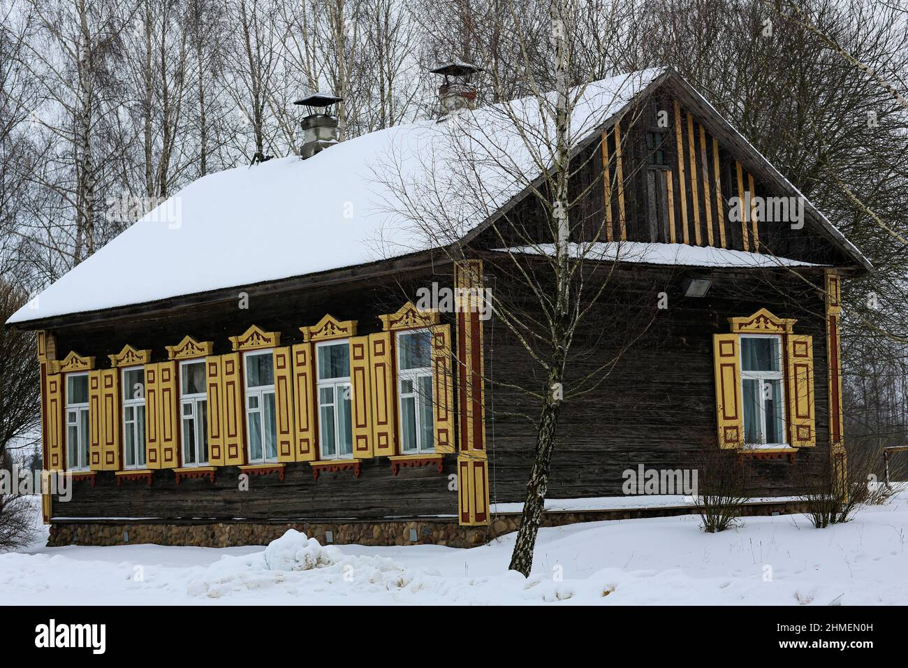 Old wooden house made of gray logs. With beautiful yellow windows and ...