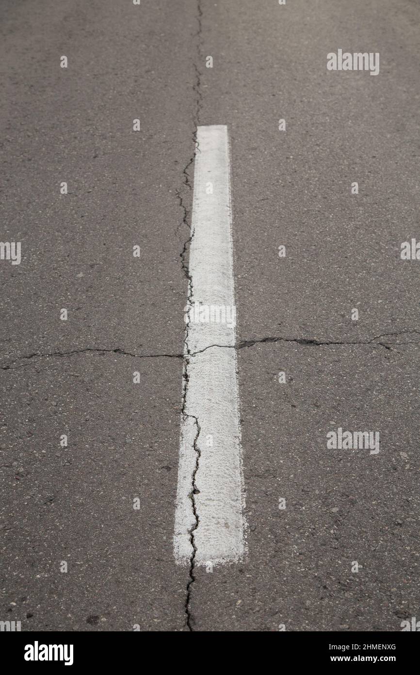 Close up of white road mark, asphalt cracks Stock Photo - Alamy
