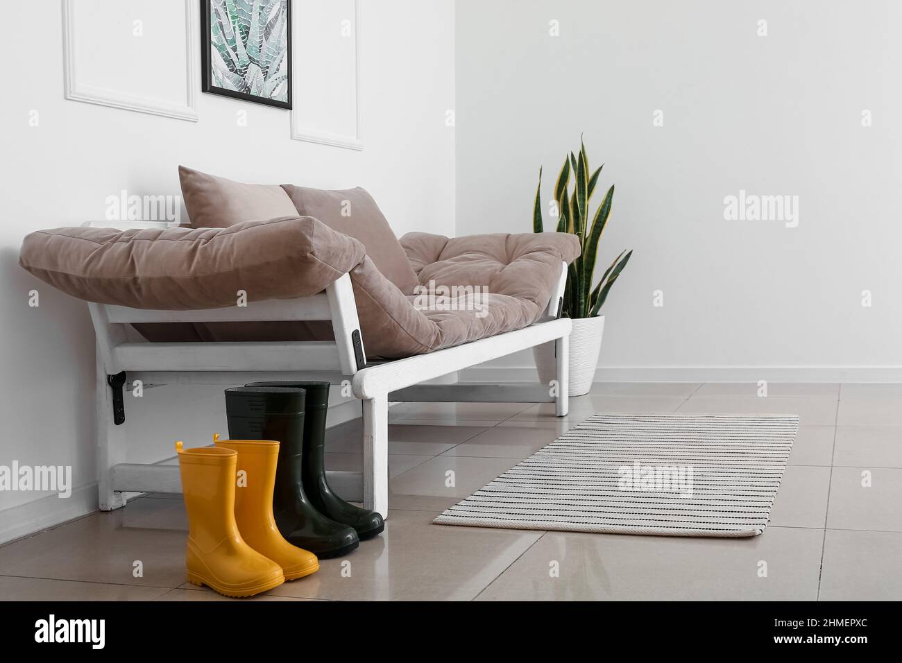Rubber boots and sofa near white wall in hallway Stock Photo - Alamy