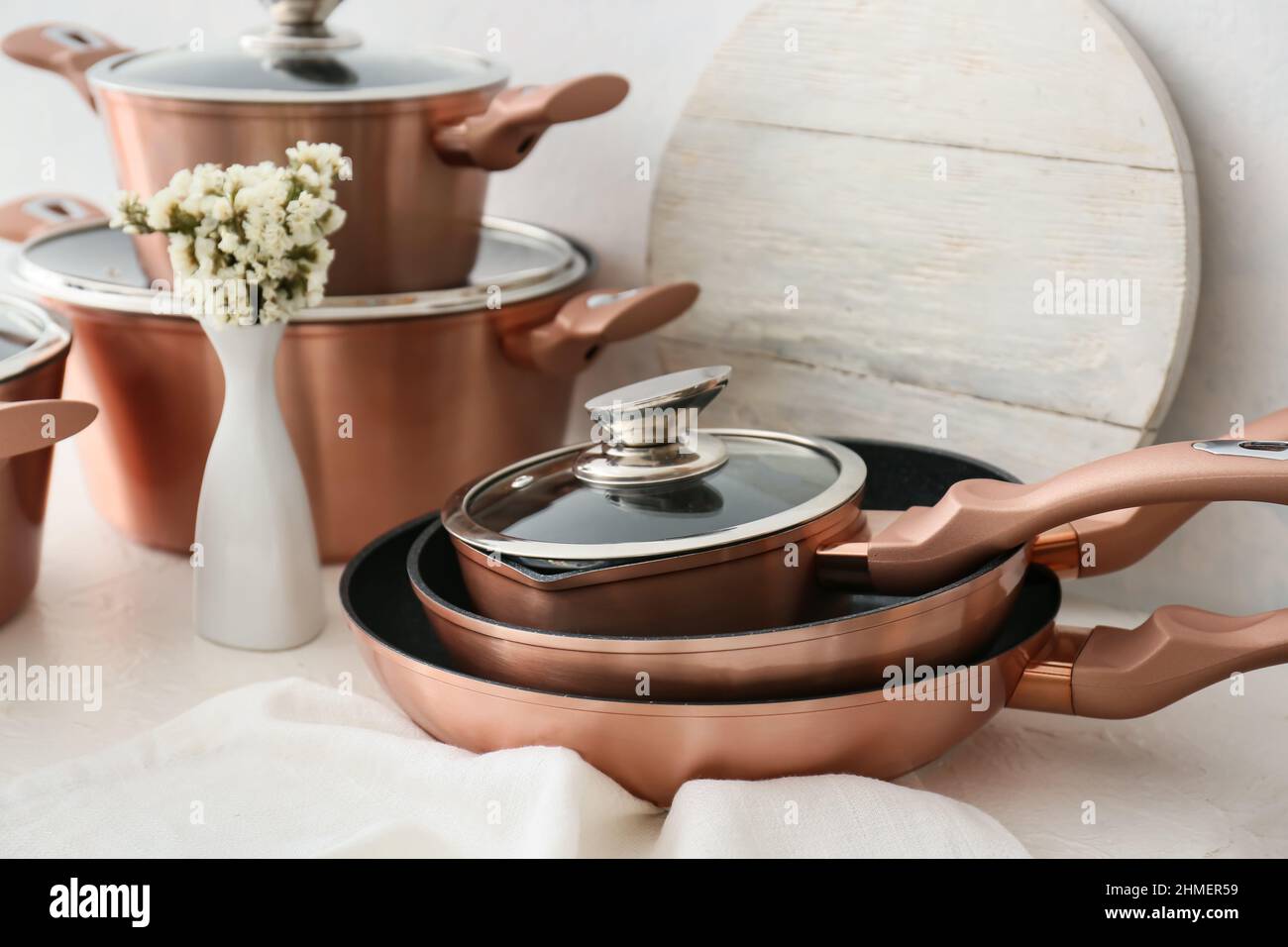 Set of copper kitchen utensils and vase with flowers on table, closeup ...