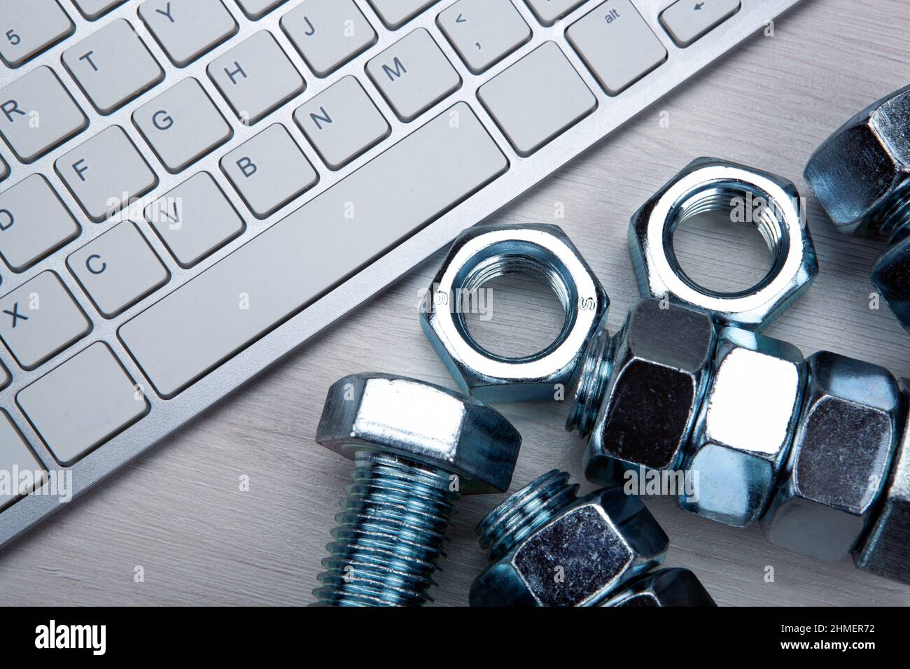 nuts screws fastening materials and pc keyboard on a wooden background ...