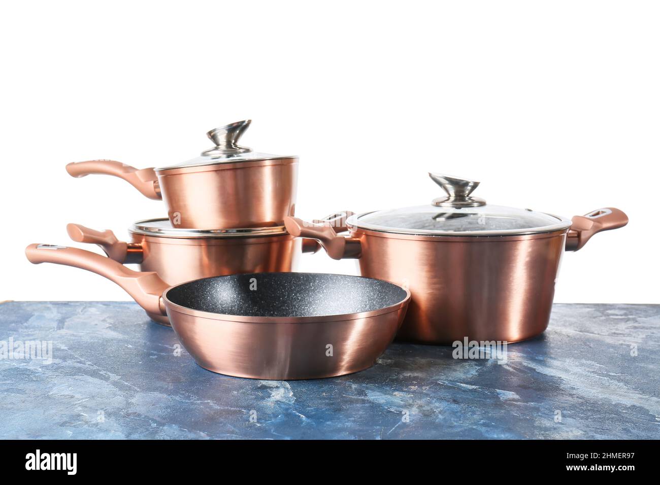 Set of copper kitchen utensils on grunge table against white background ...
