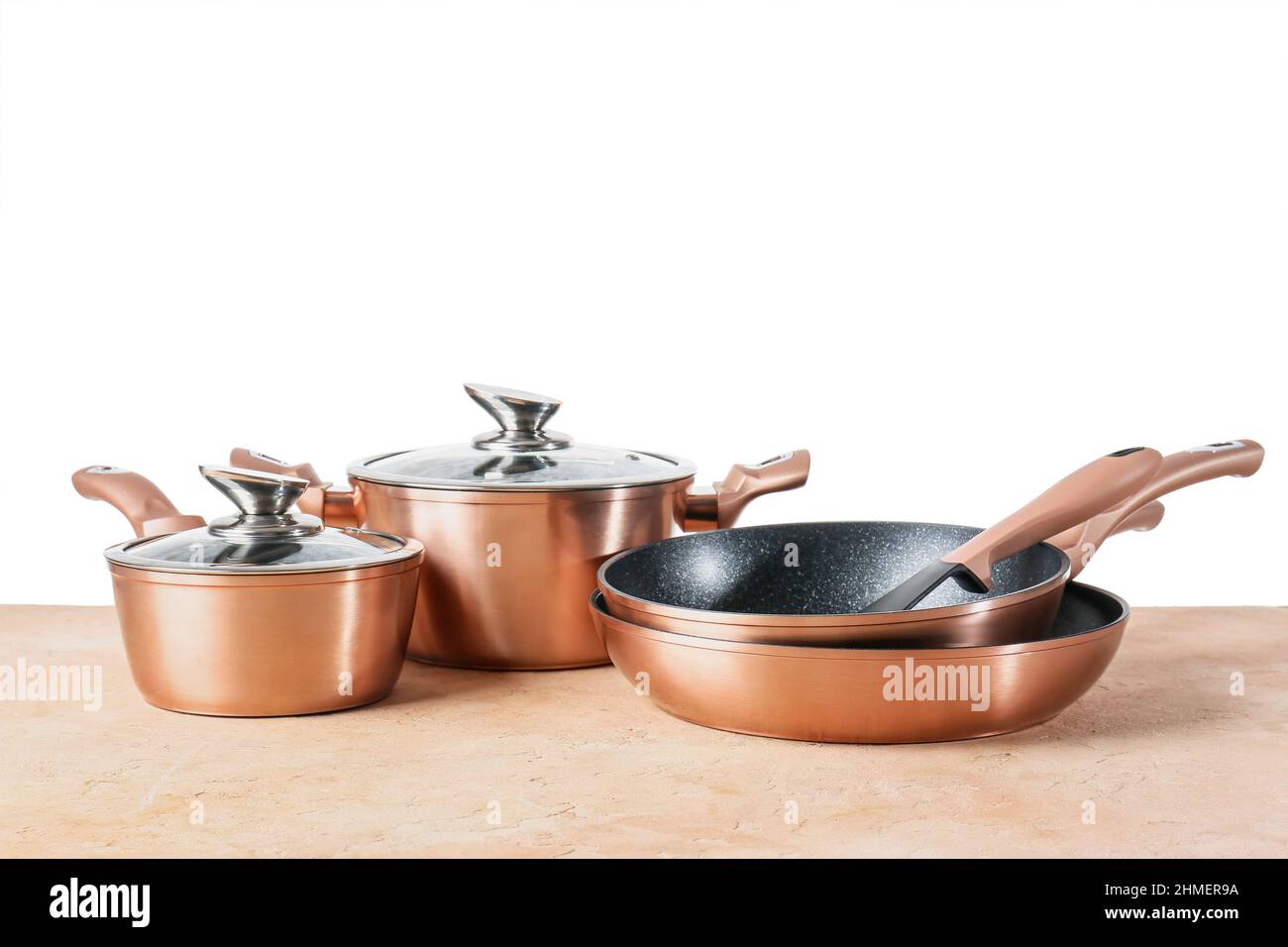 Set of copper kitchen utensils on beige table against white background ...