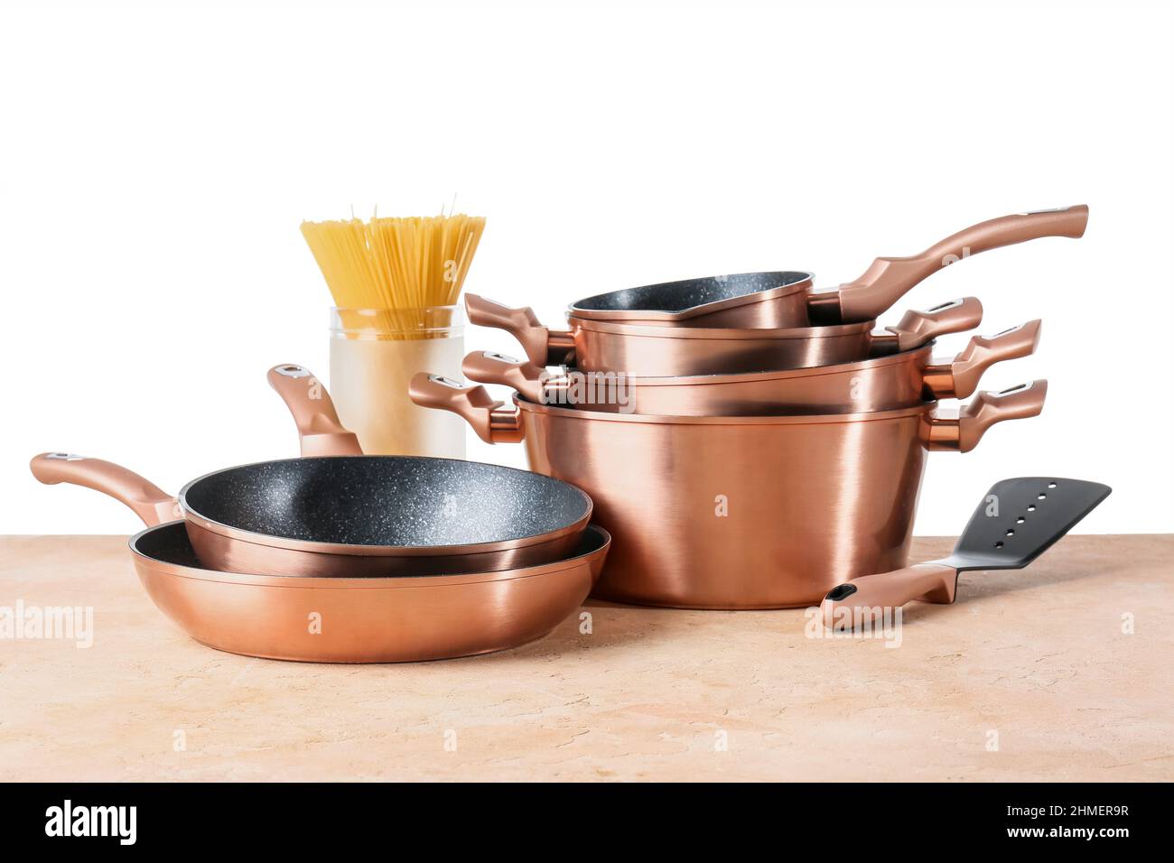 Set of copper kitchen utensils and jar with raw spaghetti on table ...