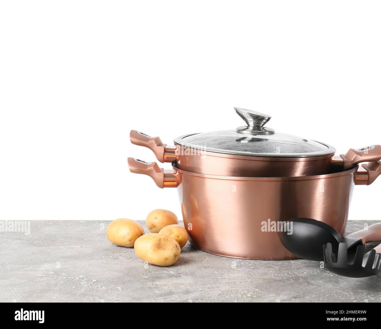 Copper kitchen utensils with raw potatoes on grunge table against white ...