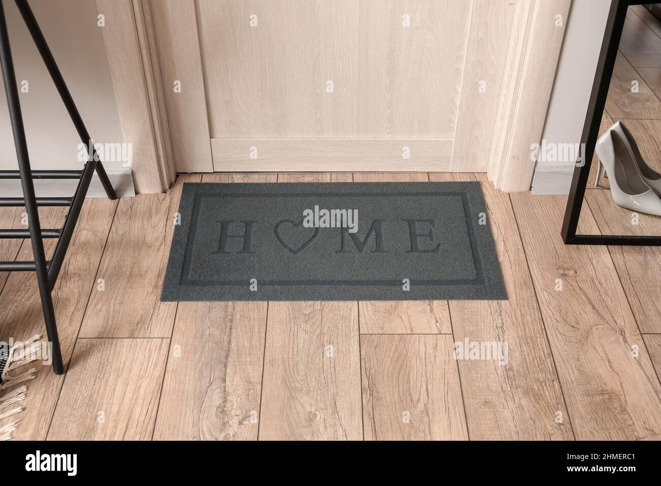 Modern mat near light wooden door in hall Stock Photo - Alamy