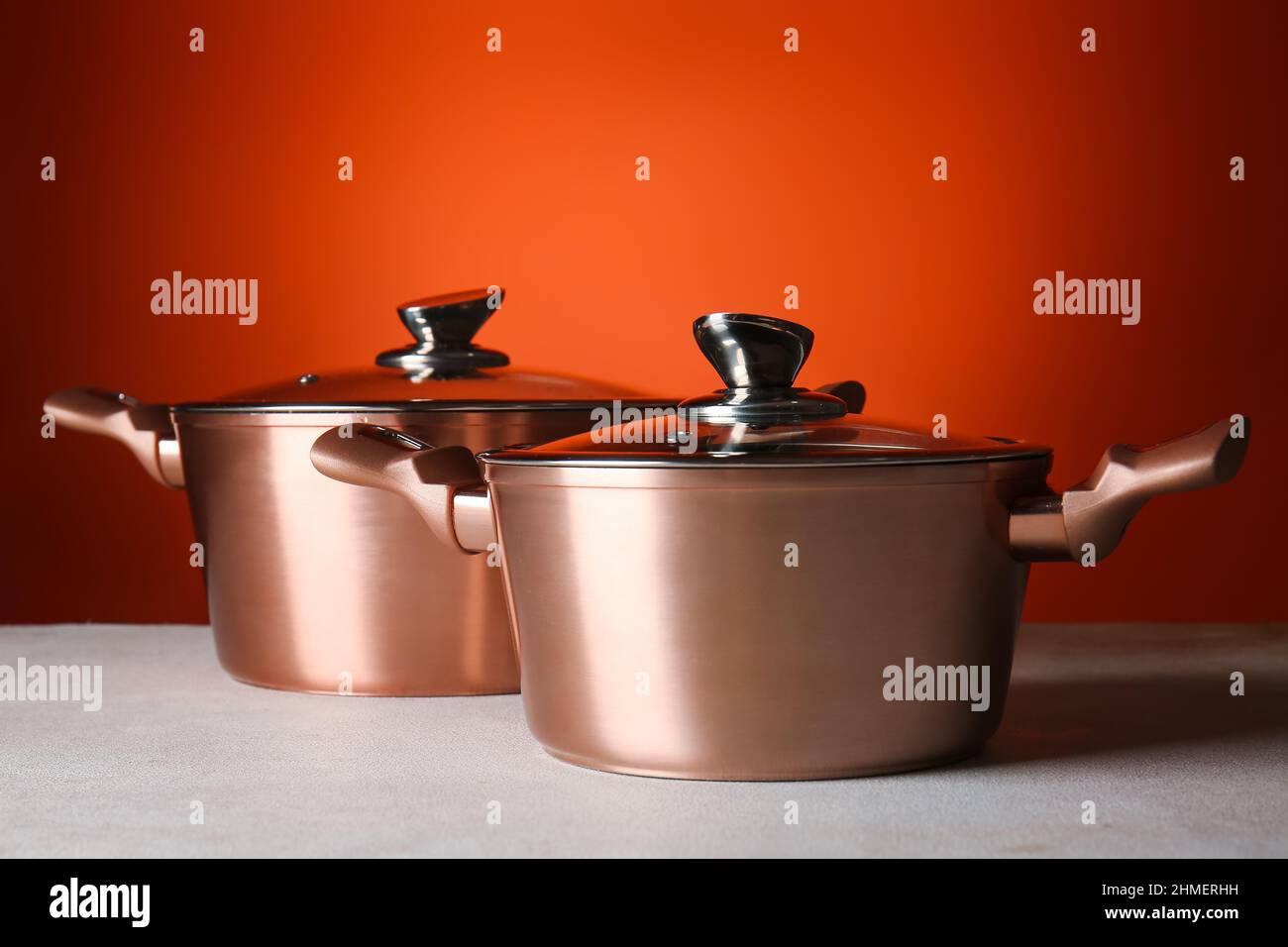 Copper cooking pots on table against red background Stock Photo - Alamy