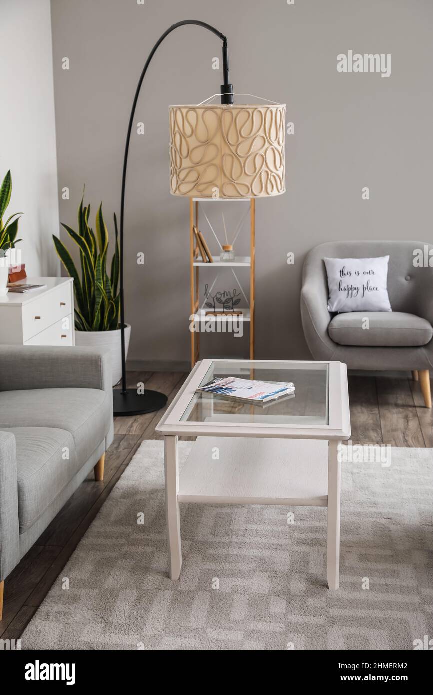 Interior of light living room with standard lamp, table and armchair ...