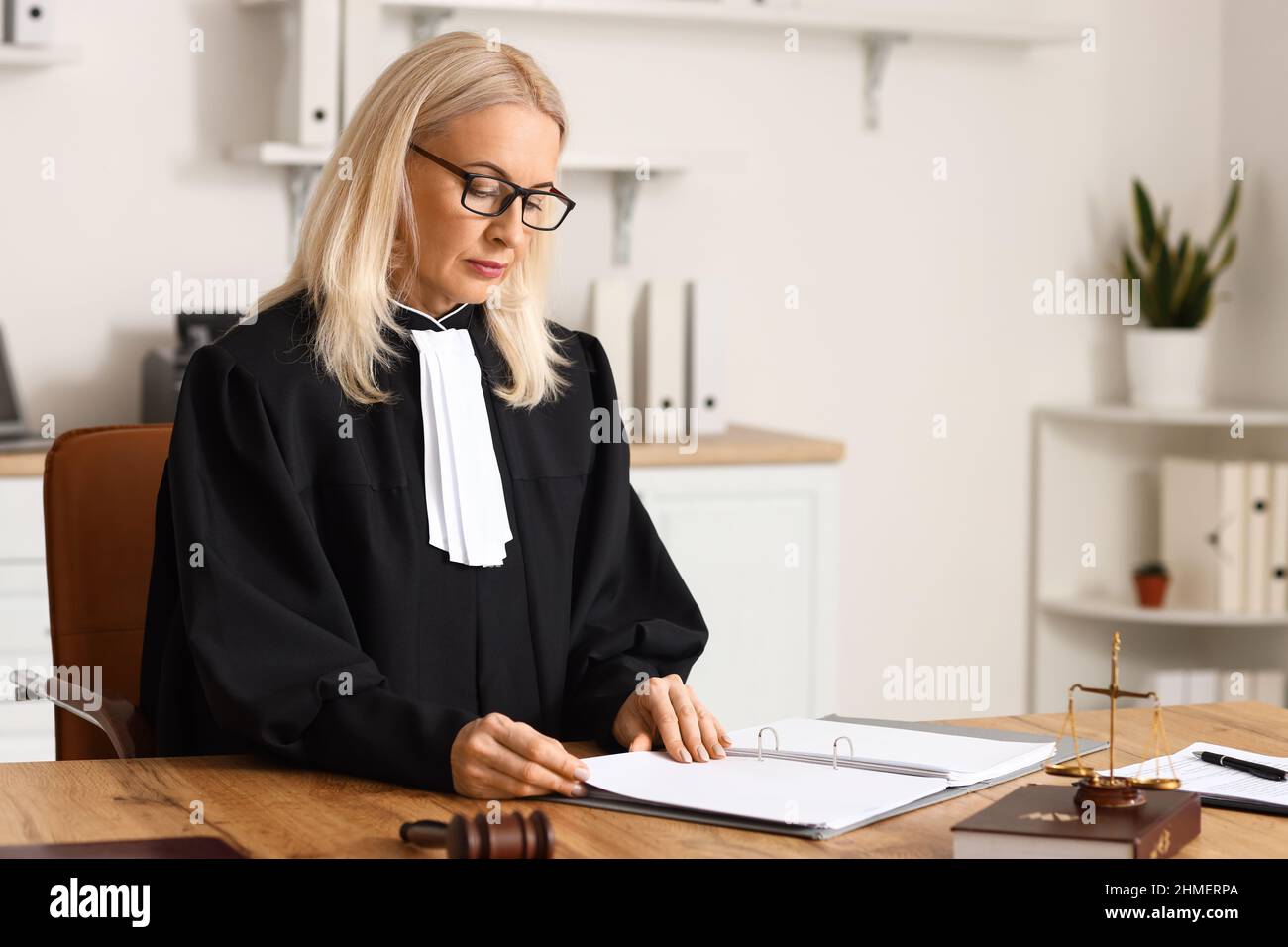 Mature female judge working with documents at table in courtroom Stock ...
