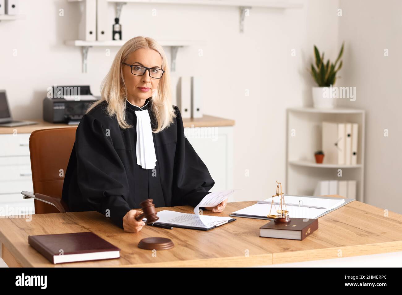 Mature female judge with gavel and document working at table in ...
