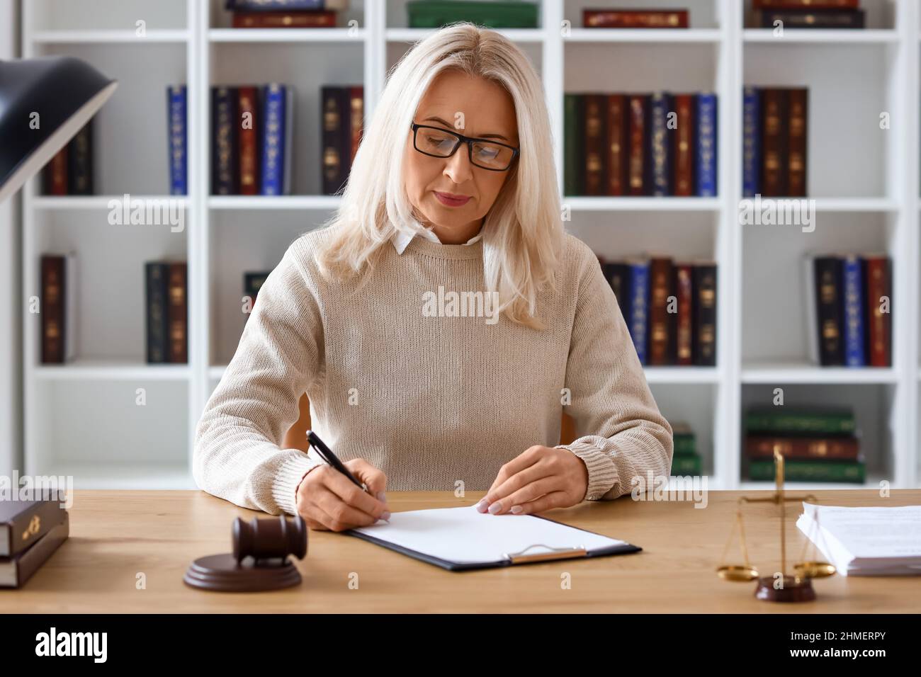 Mature female judge working with document at table in courtroom Stock ...