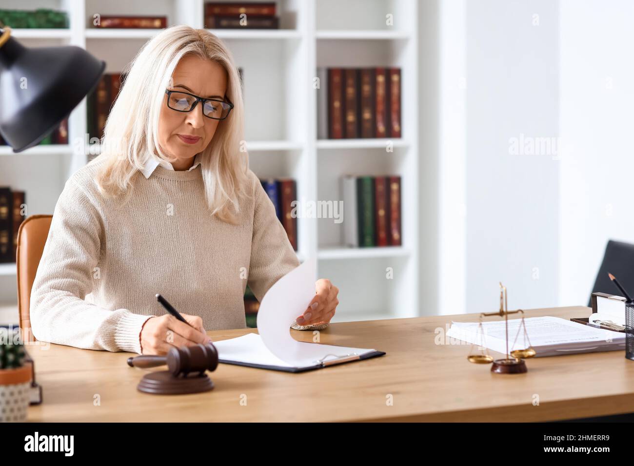Mature female judge working with document at table in courtroom Stock ...