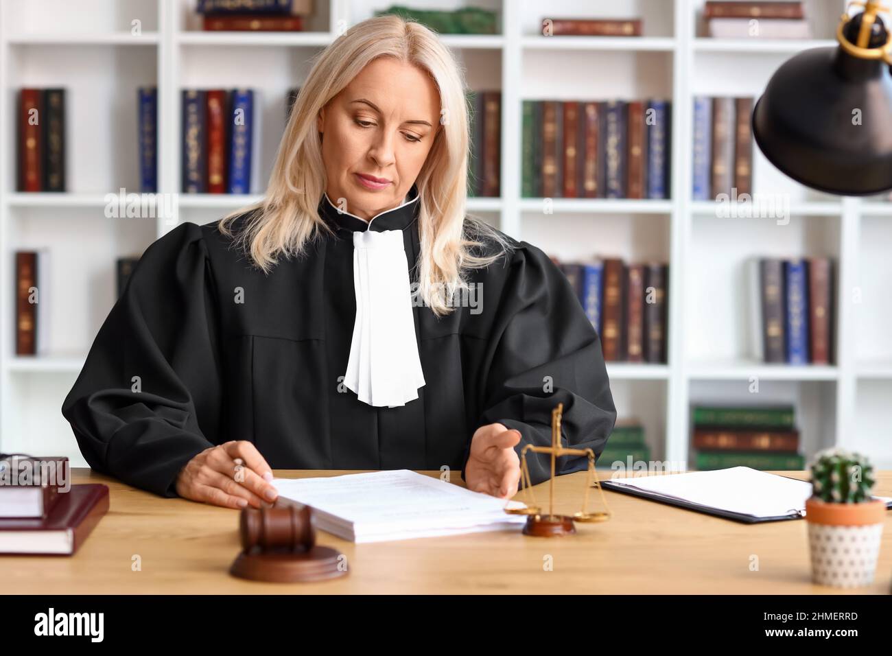 Mature female judge working with documents at table in courtroom Stock ...